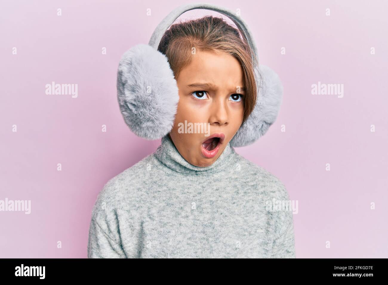 Little beautiful girl wearing fluffy earmuff angry and mad screaming ...
