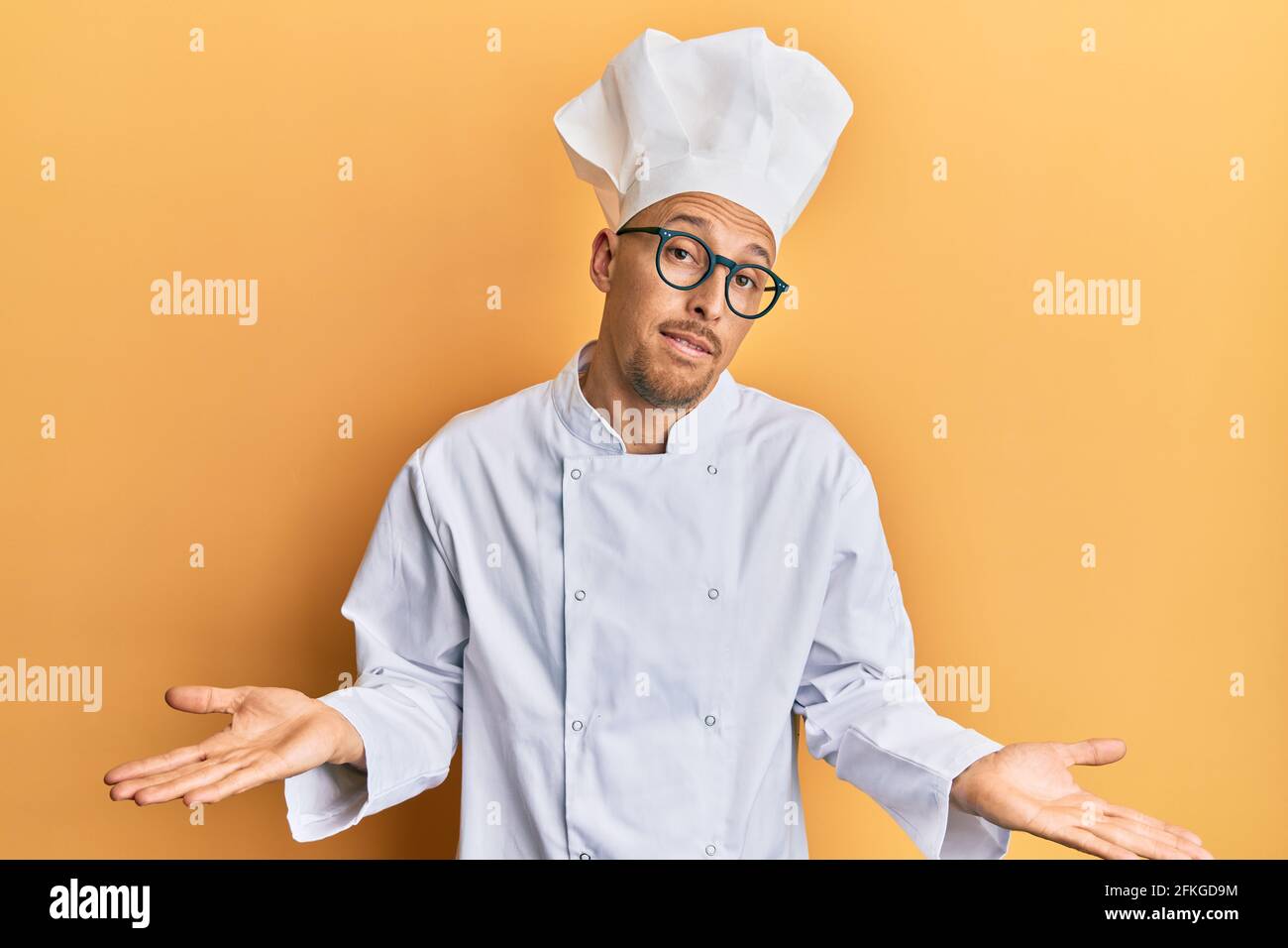 Bald man with beard wearing professional cook uniform clueless and ...