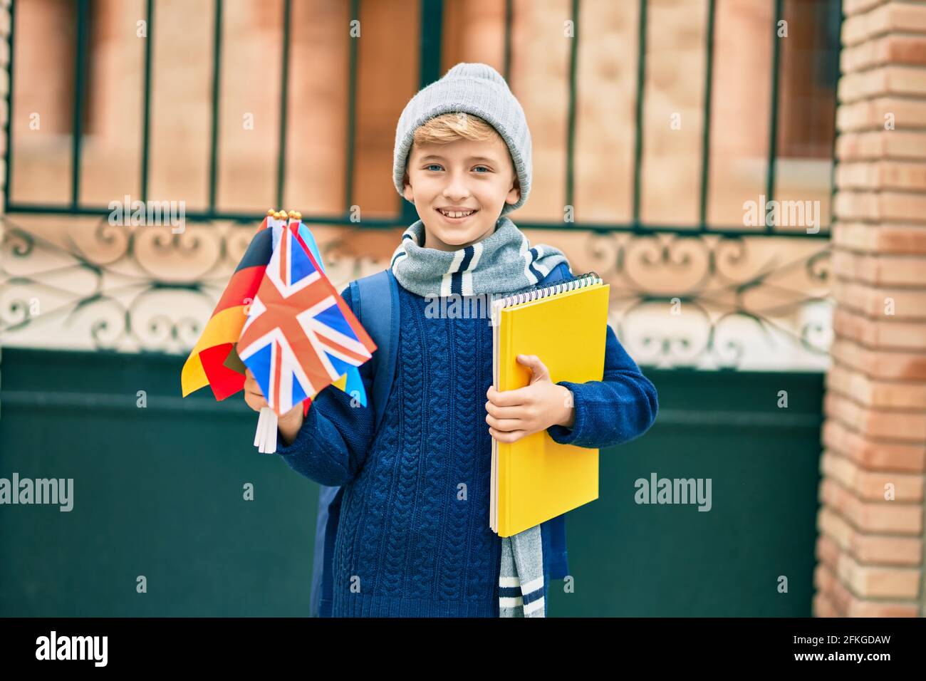 Adorable blond student kid smiling happy holding flags of different ...
