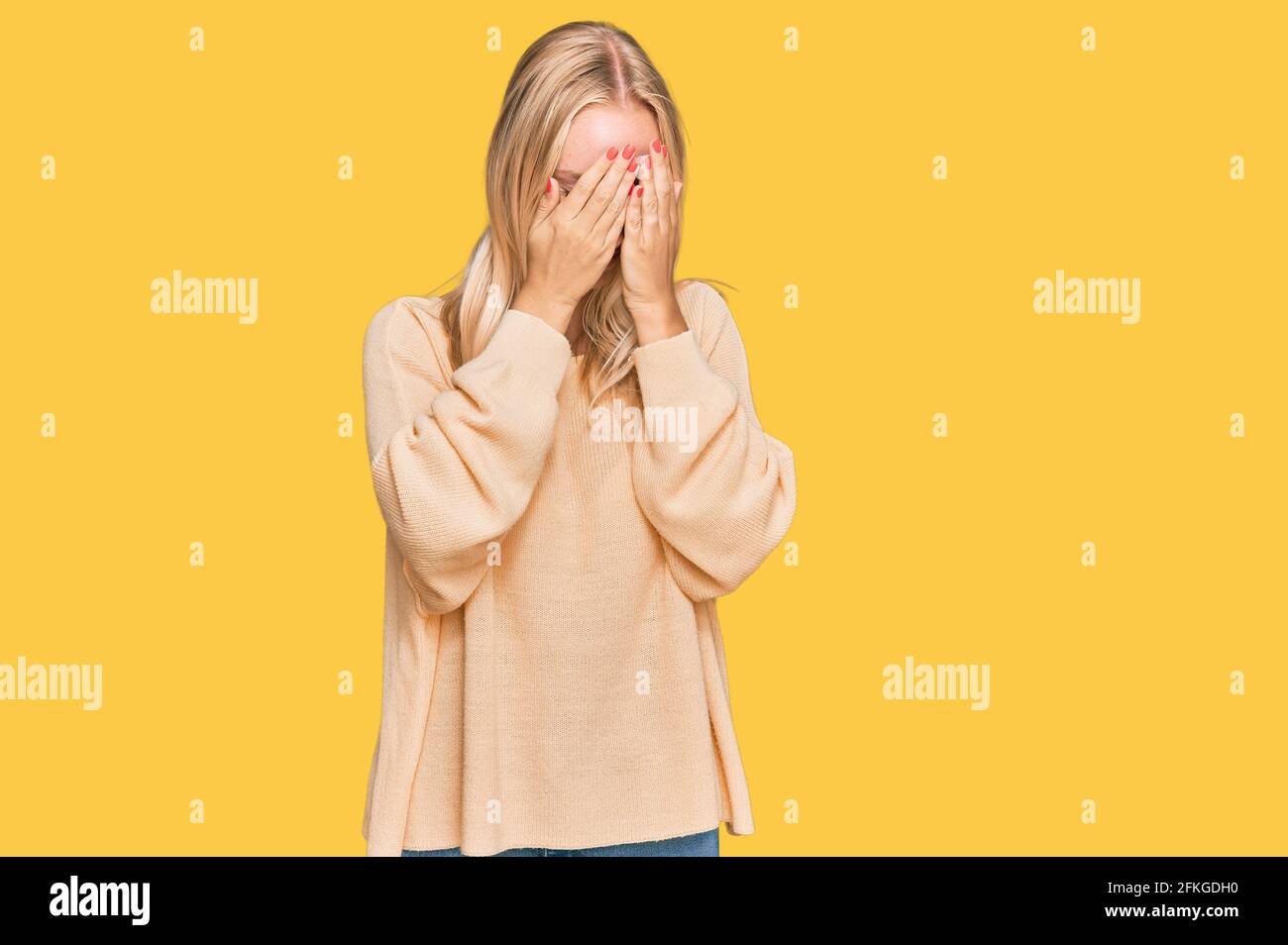 Young blonde girl wearing casual clothes with sad expression covering ...