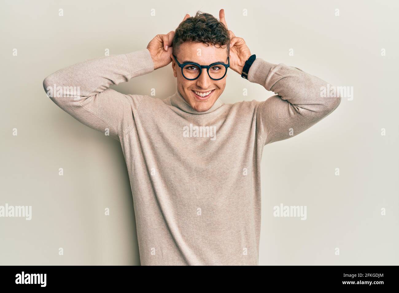 Hispanic young man wearing casual turtleneck sweater posing funny and ...