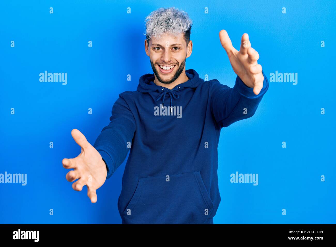 Young hispanic man with modern dyed hair wearing casual blue sweatshirt ...