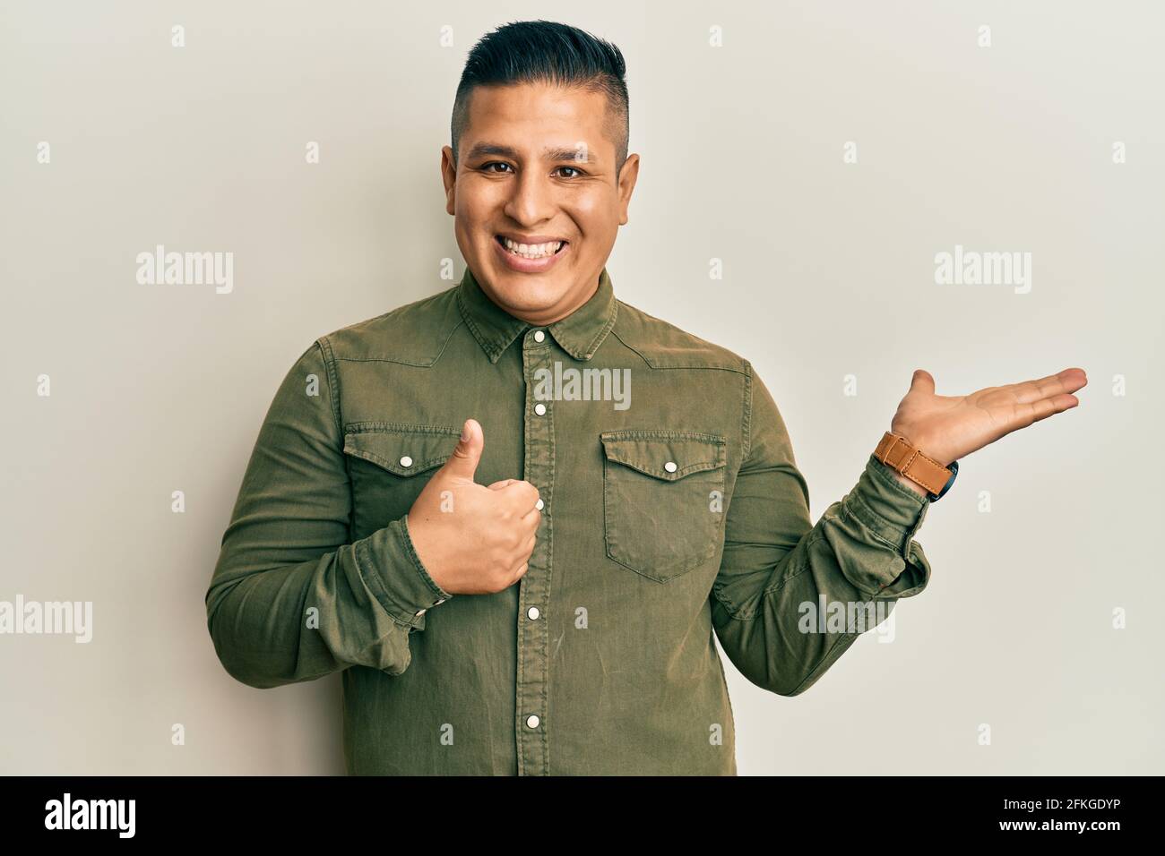 Young latin man wearing casual clothes showing palm hand and doing ok ...