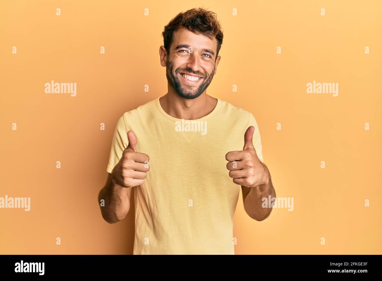 Handsome man with beard wearing casual yellow tshirt over yellow ...