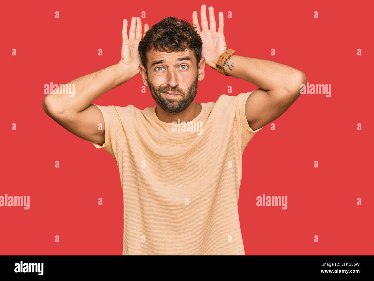 Handsome young man with beard wearing casual tshirt doing bunny ears ...