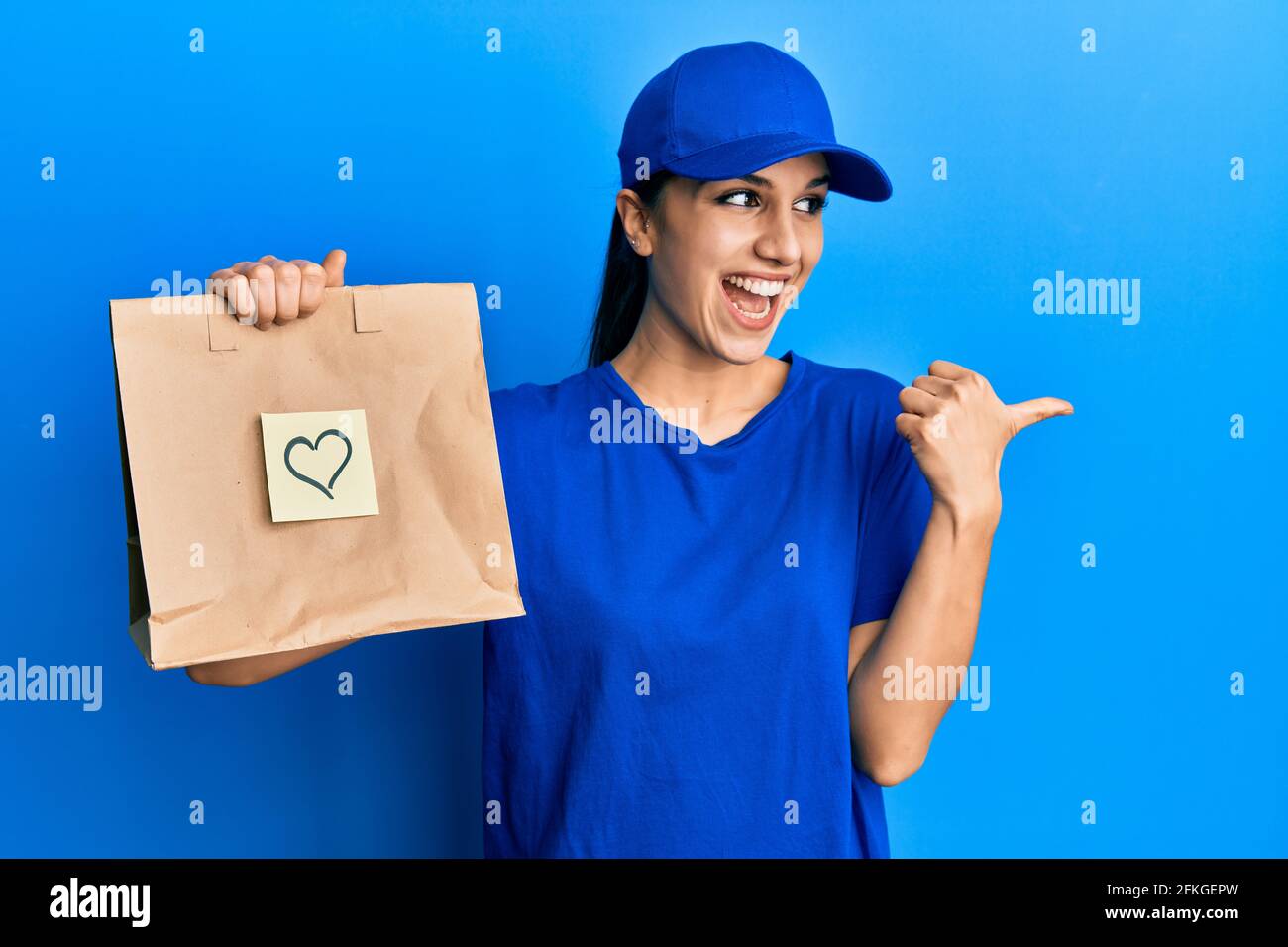 Young hispanic woman holding take away paper bag with heart reminder ...