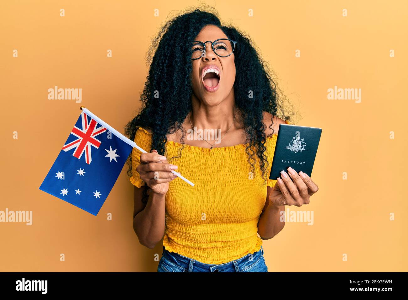 Middle age african american woman holding australian flag and passport ...