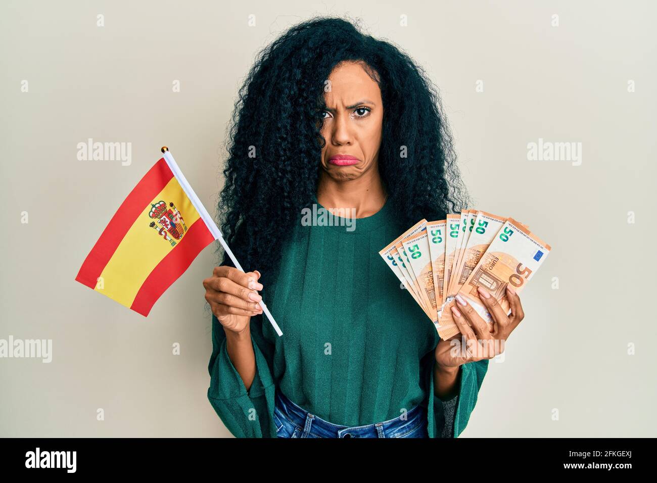 Middle age african american woman holding spain flag and euros ...