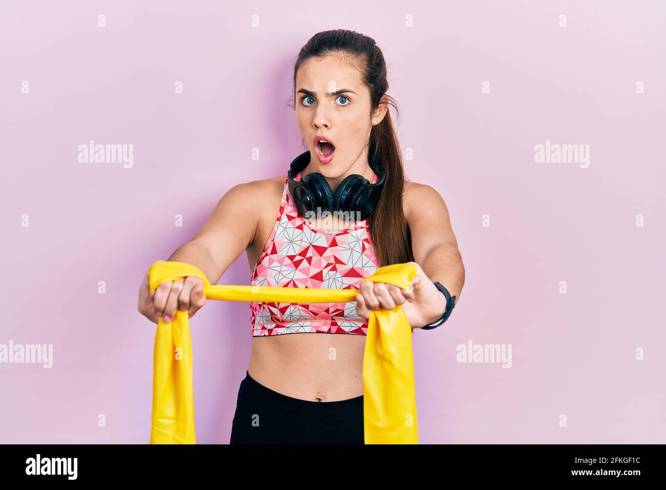 Young brunette teenager training arm resistance with elastic arm bands ...