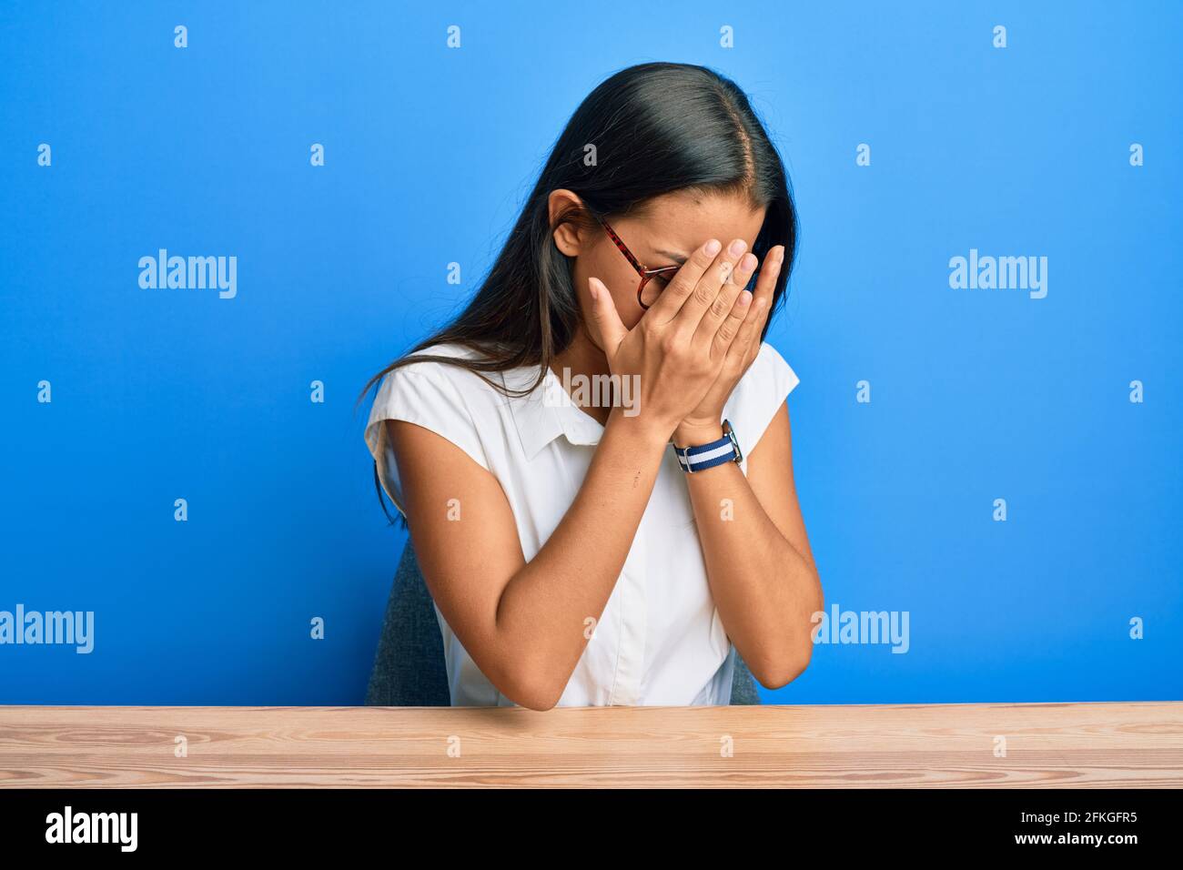Beautiful hispanic woman wearing casual clothes sitting on the table ...