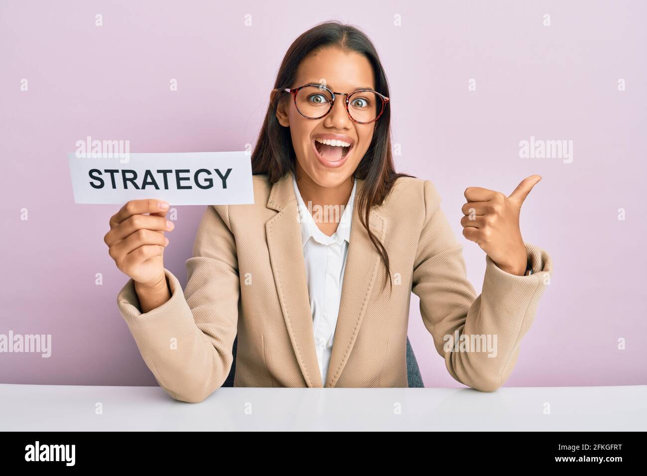 Beautiful hispanic business woman holding strategy word on paper ...