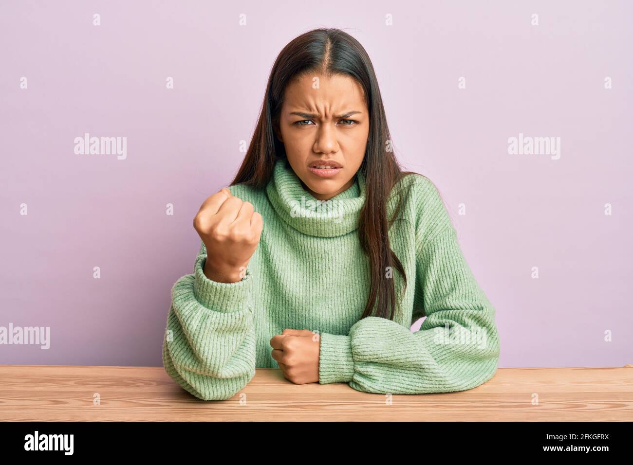 Beautiful hispanic woman wearing casual clothes sitting on the table ...