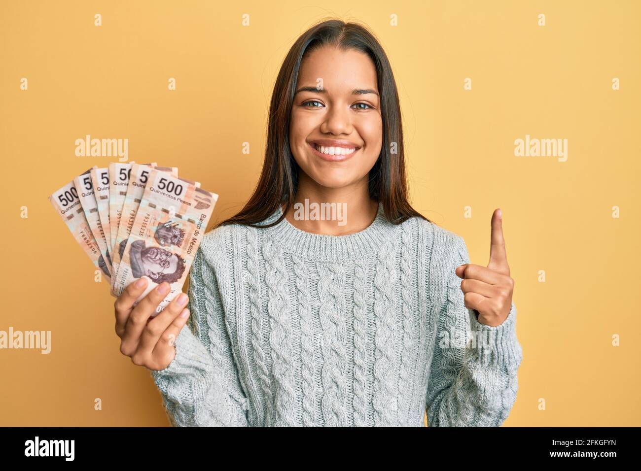 Beautiful hispanic woman holding 500 mexican pesos banknotes smiling ...