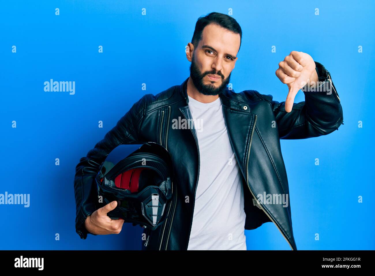 Young man with beard holding motorcycle helmet with angry face ...