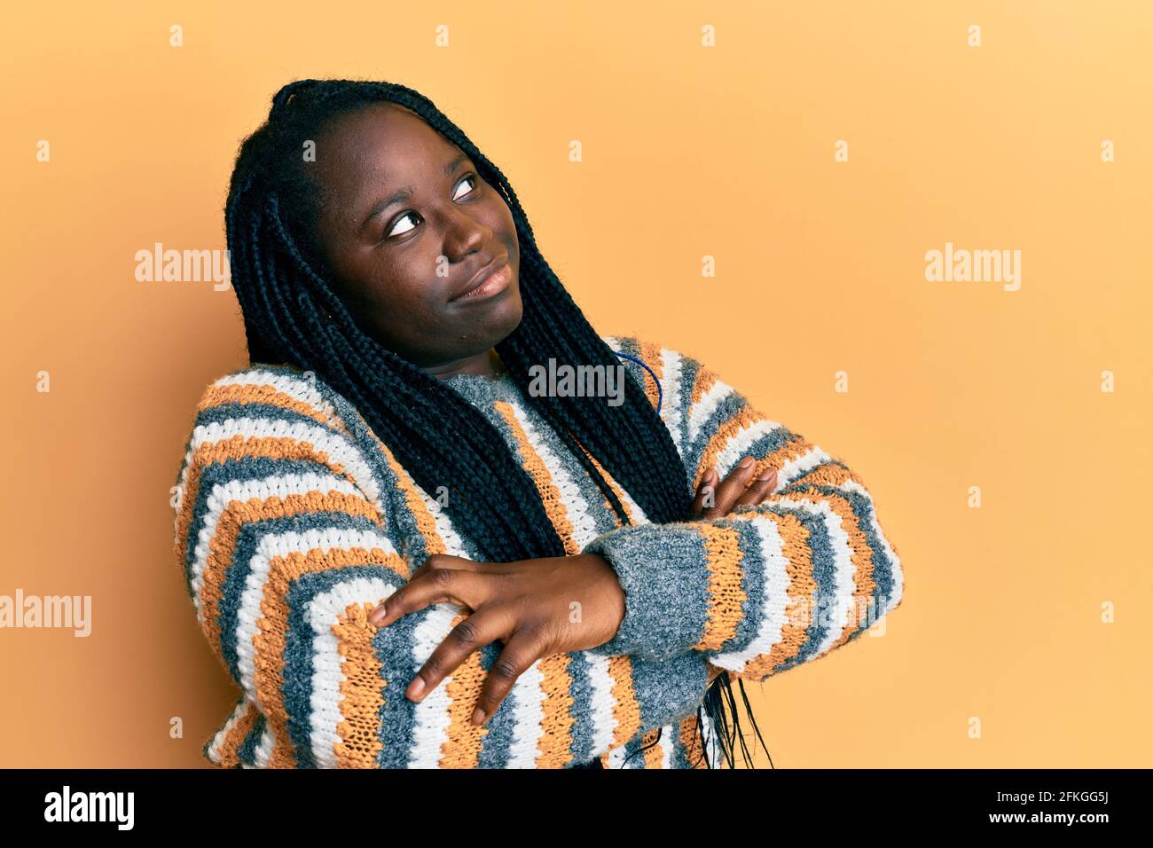 Young black woman with braids wearing casual winter sweater looking to ...