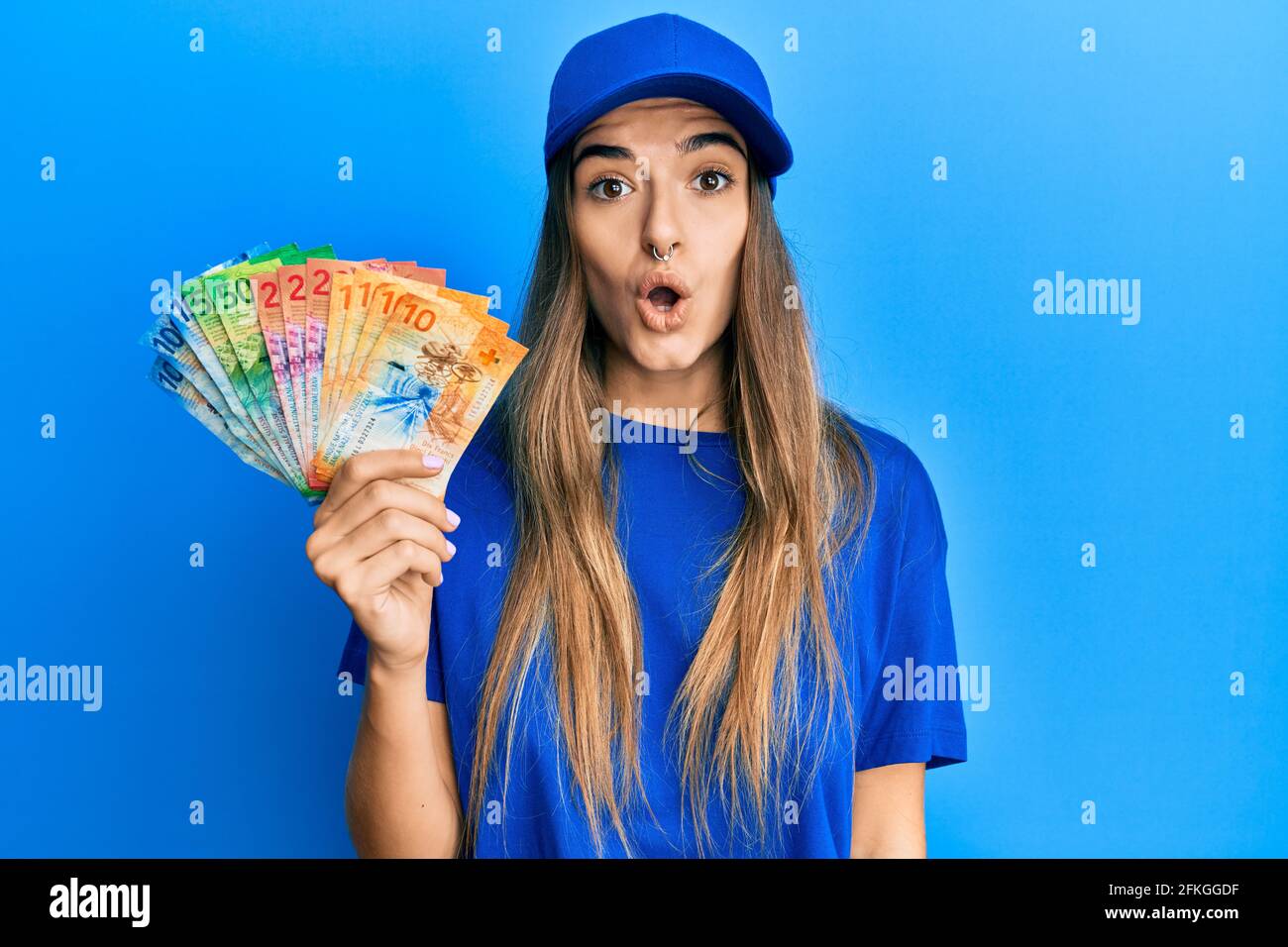 Young hispanic woman wearing delivery uniform and cap holding swiss ...