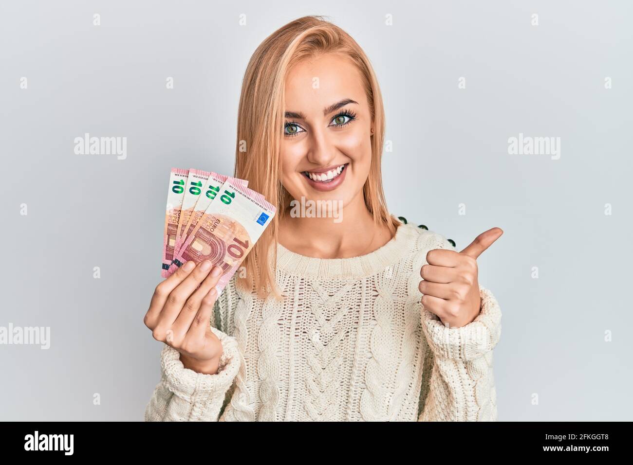 Beautiful caucasian blonde woman holding 10 euro banknotes smiling ...