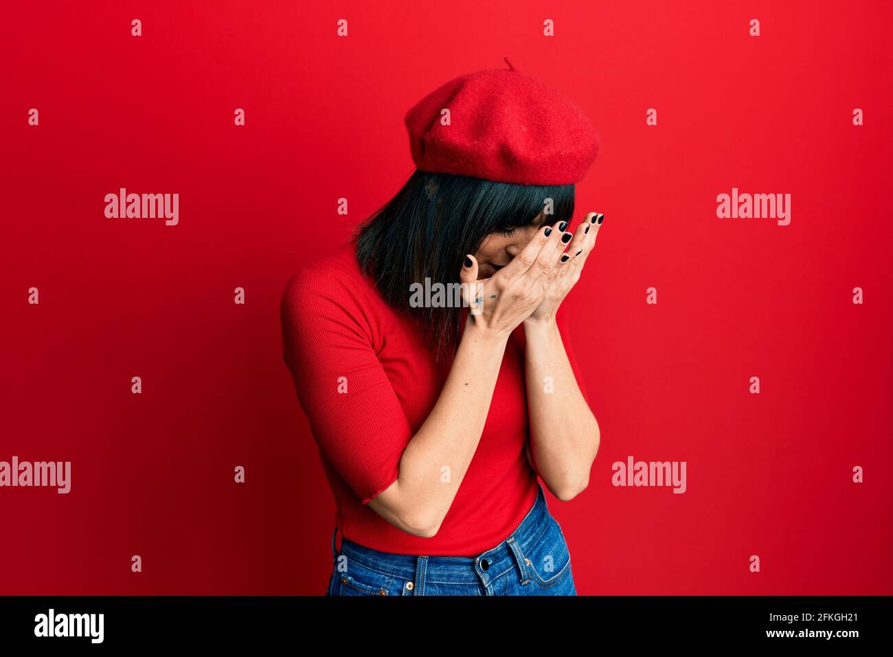 Young hispanic woman wearing french look with beret with sad expression ...