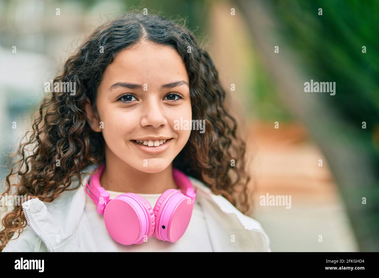Hispanic child girl smiling happy using headphones at the city Stock ...