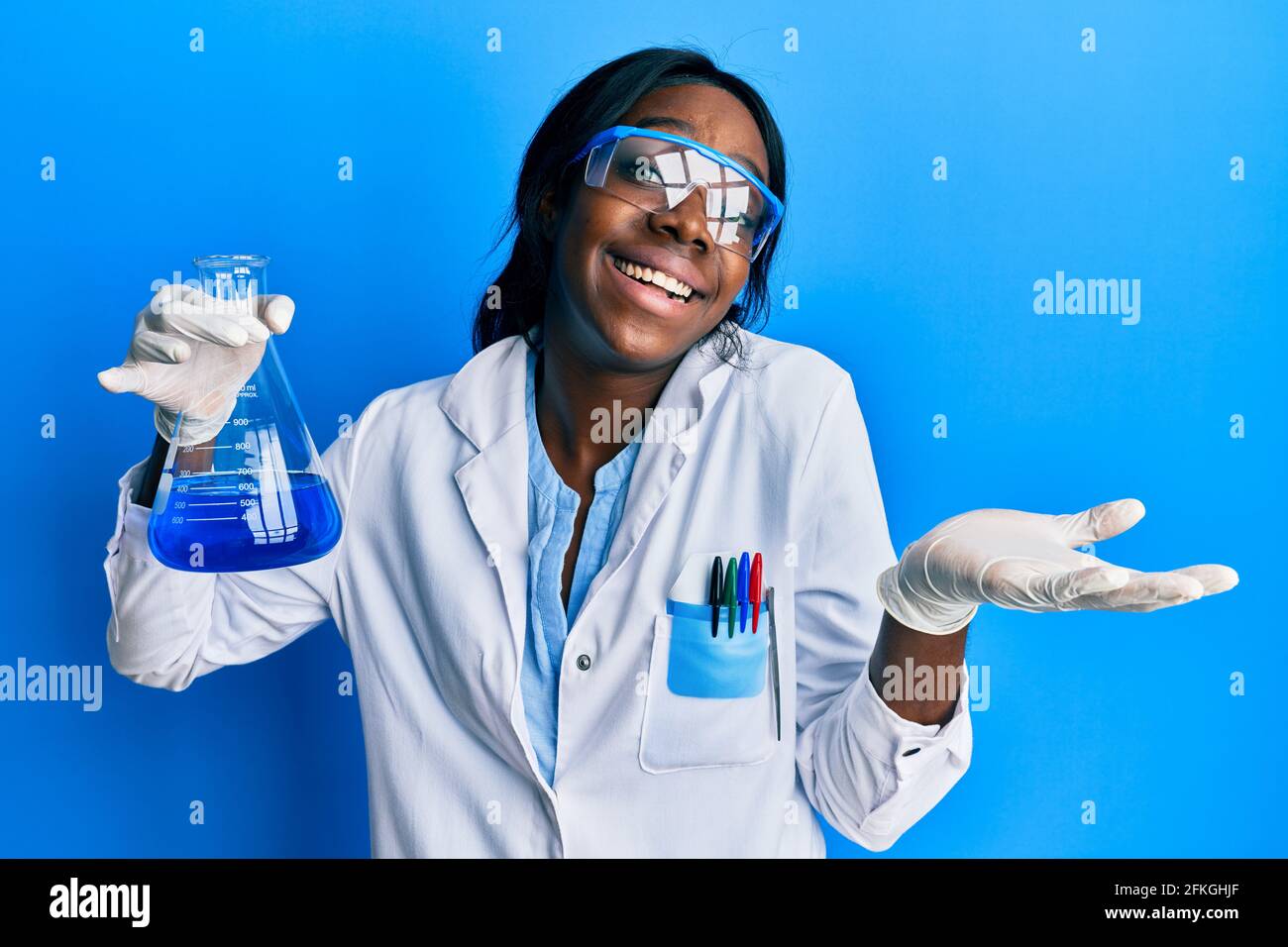 Young african american woman wearing scientist uniform holding test ...