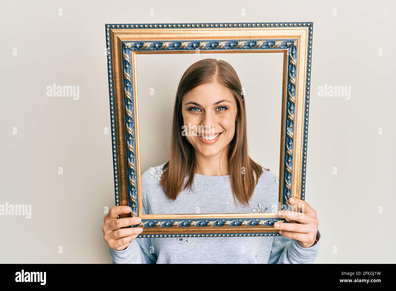 Beautiful caucasian woman holding empty frame smiling with a happy and ...
