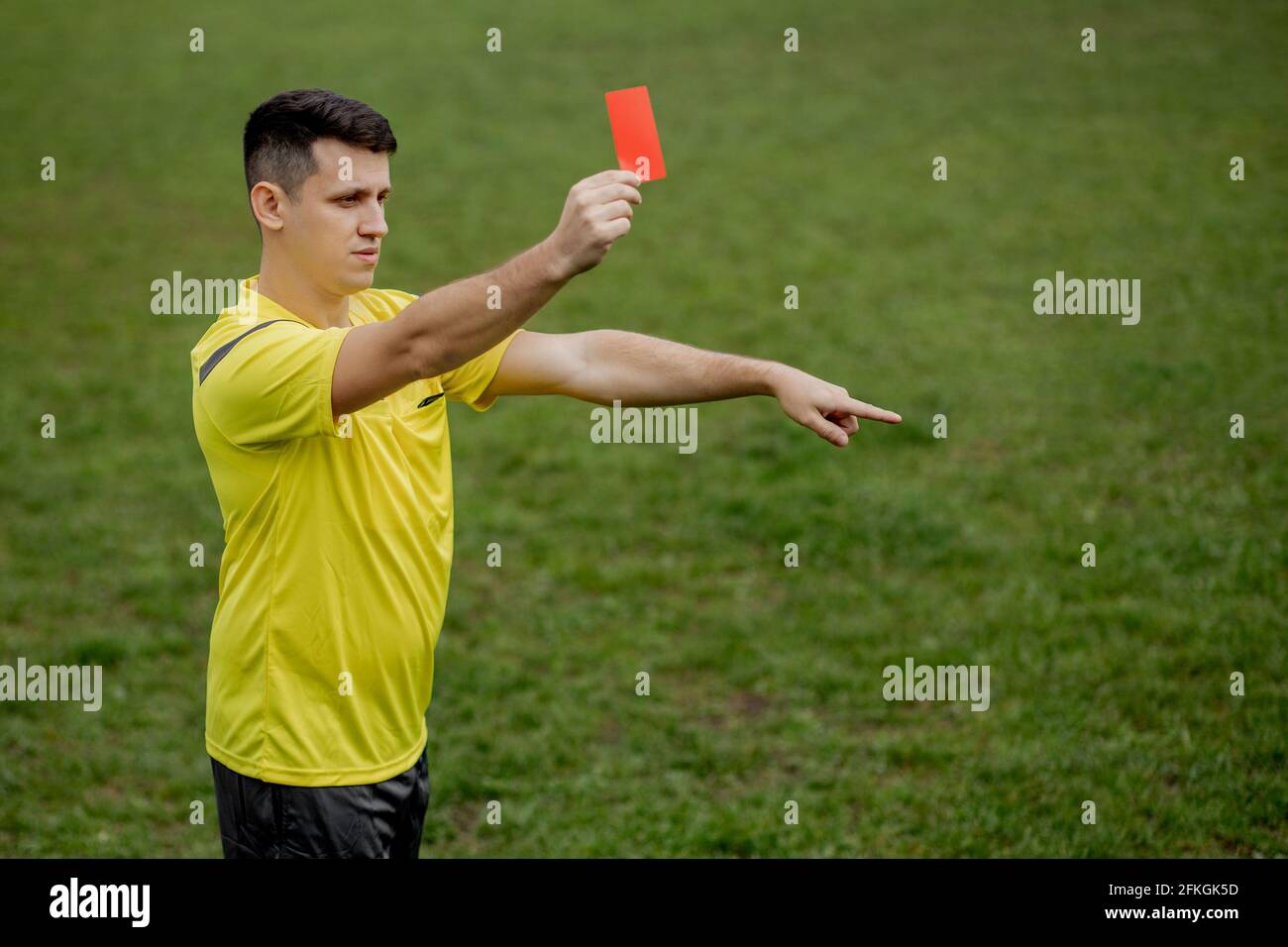 Angry football referee showing a red card and pointing with his hand on ...