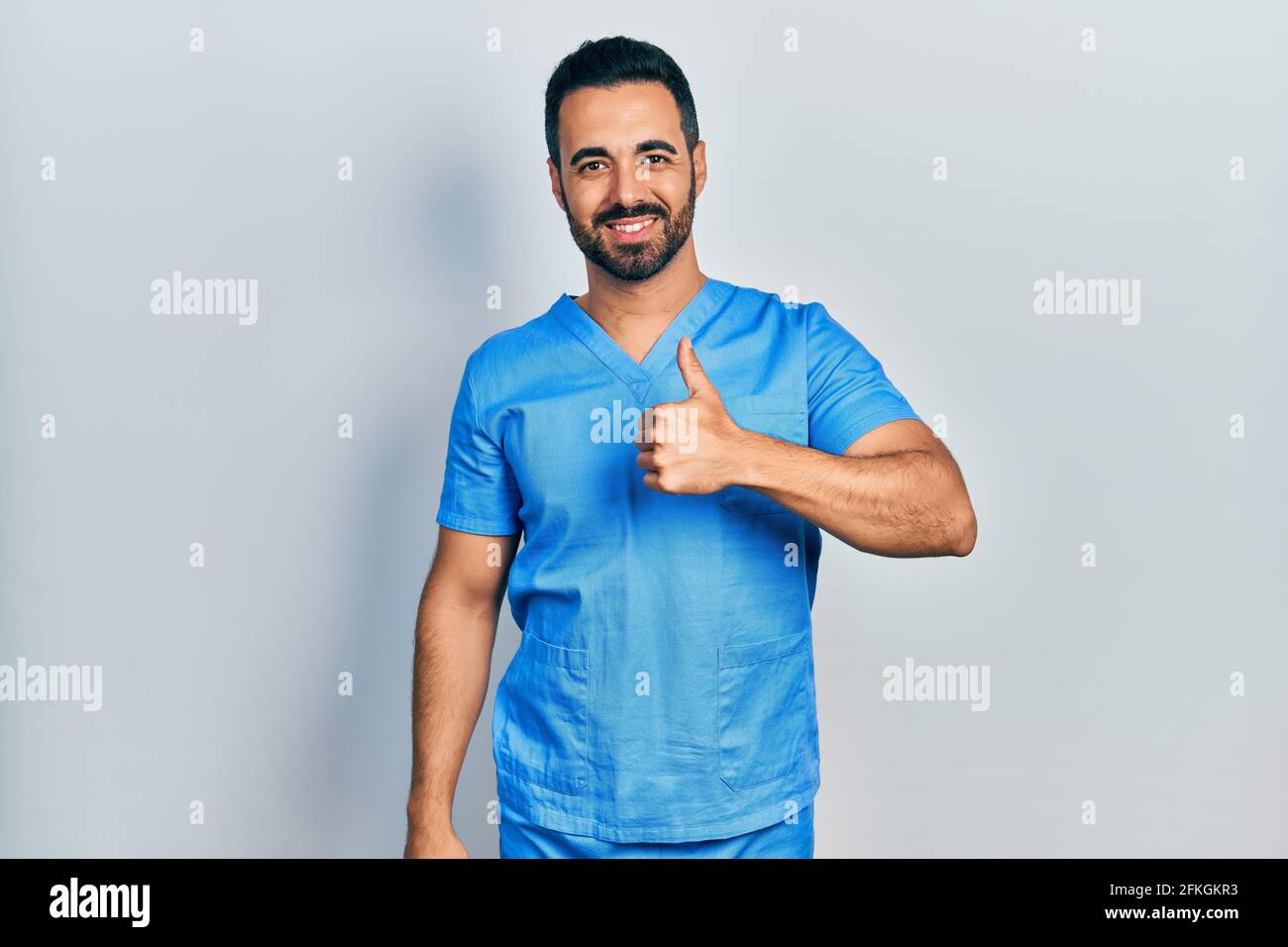 Handsome hispanic man with beard wearing blue male nurse uniform doing ...