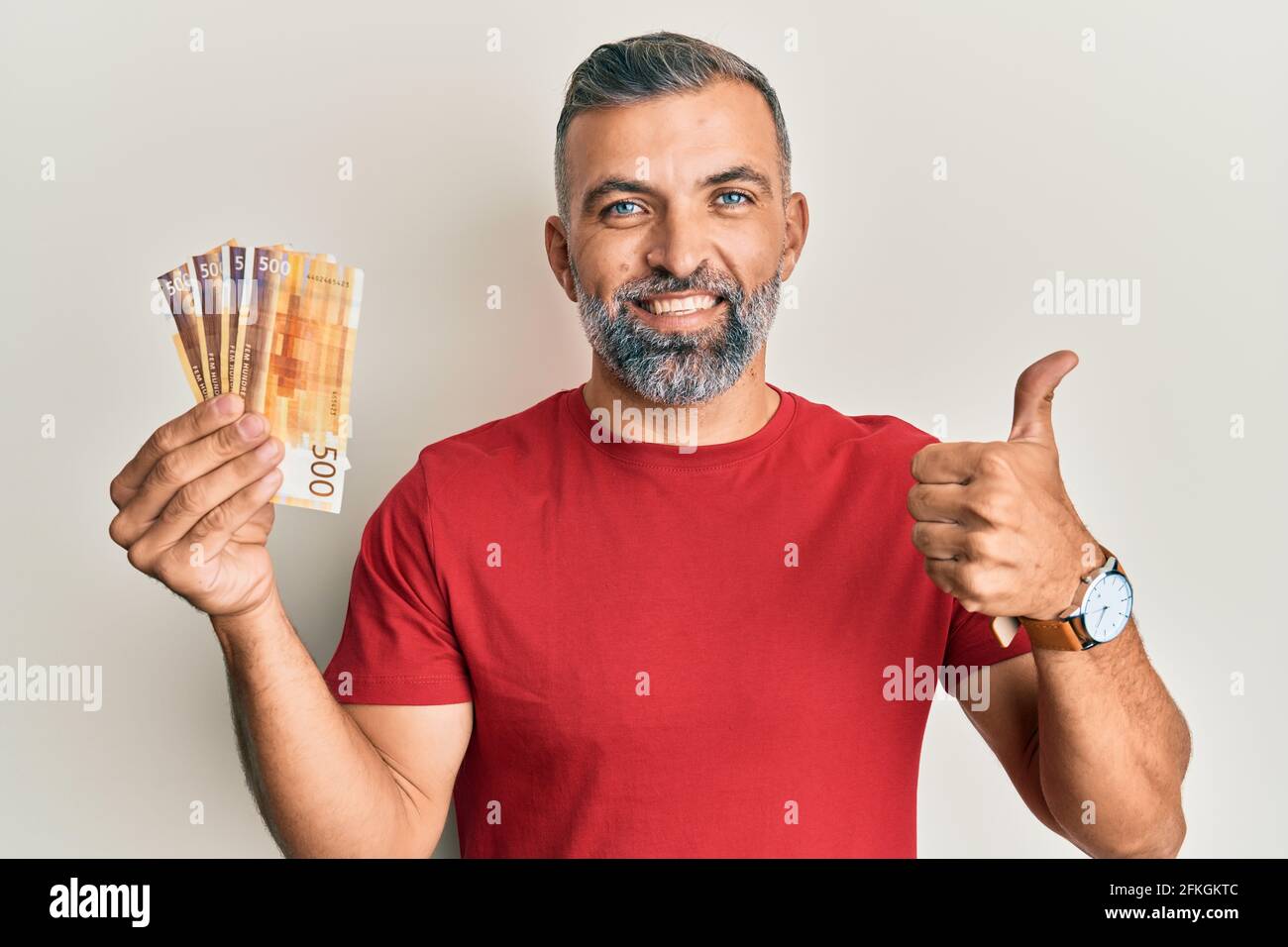 Middle age handsome man holding 500 norwegian krone banknotes smiling ...