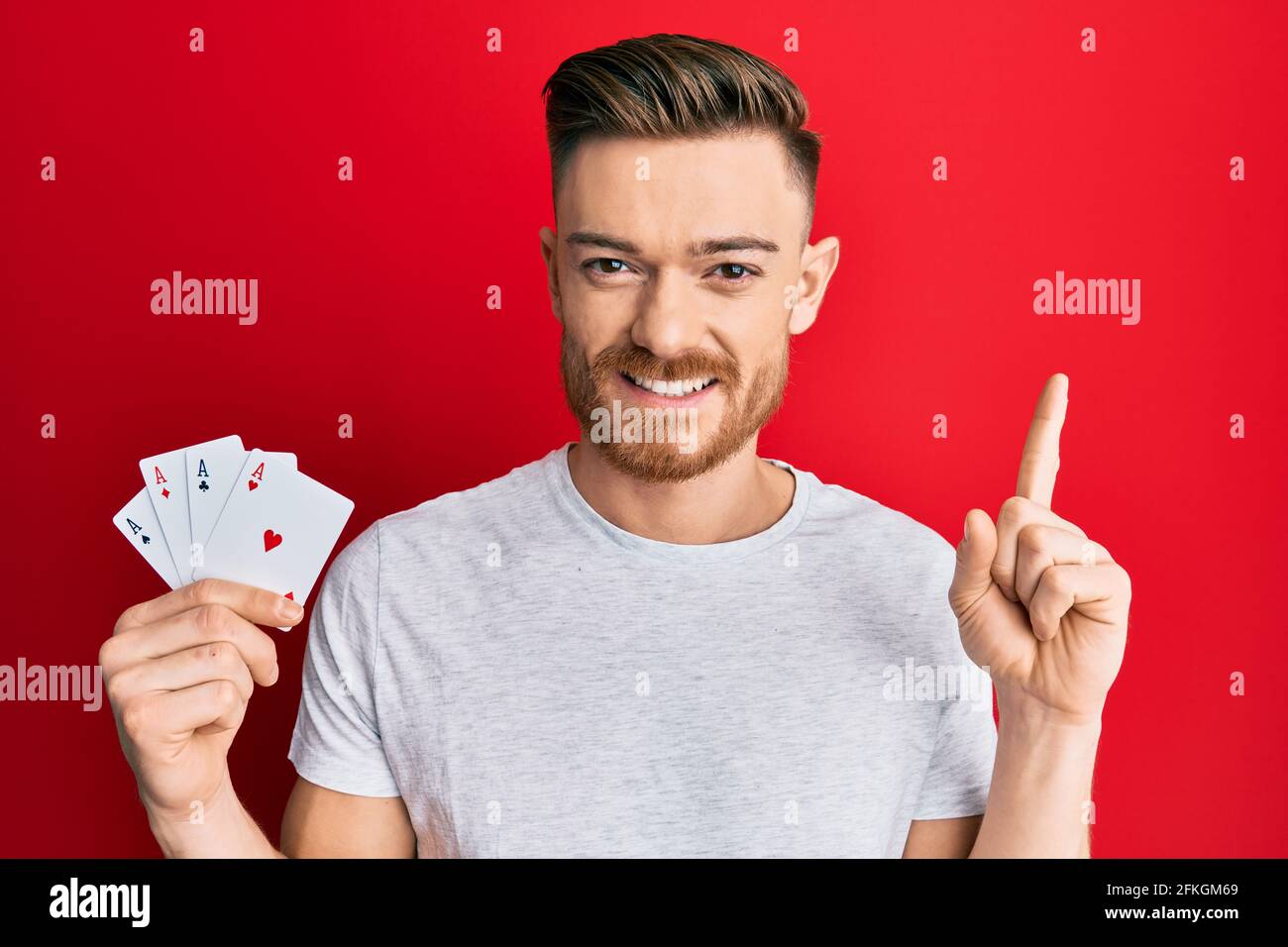 Young redhead man holding ace poker cards smiling with an idea or ...