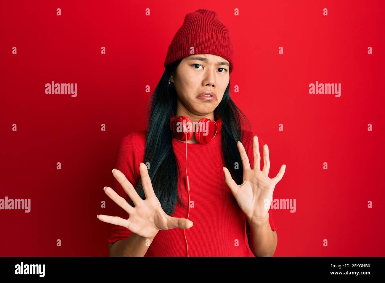 Young chinese woman listening to music using headphones disgusted ...
