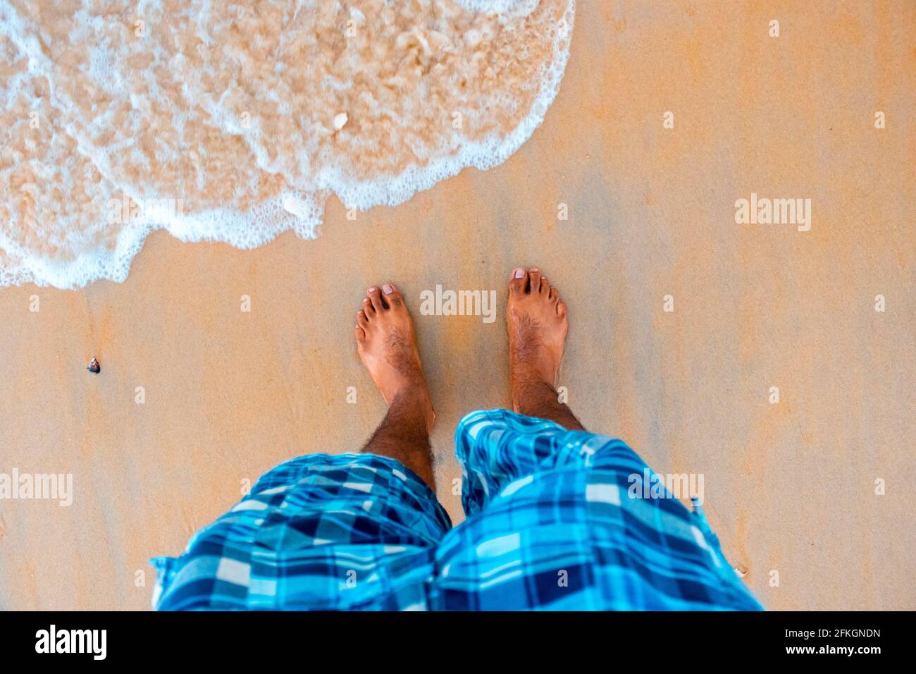 Top view shot of man's feet on the sea sand with bubble float wave ...