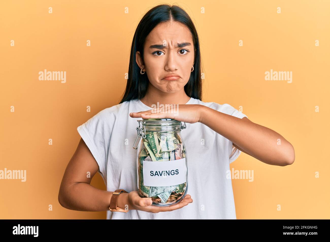 Young asian woman holding jar with savings depressed and worry for ...
