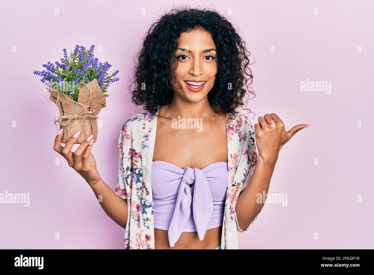 Young Latin Girl Holding Lavender Plant Pointing Thumb Up To The Side