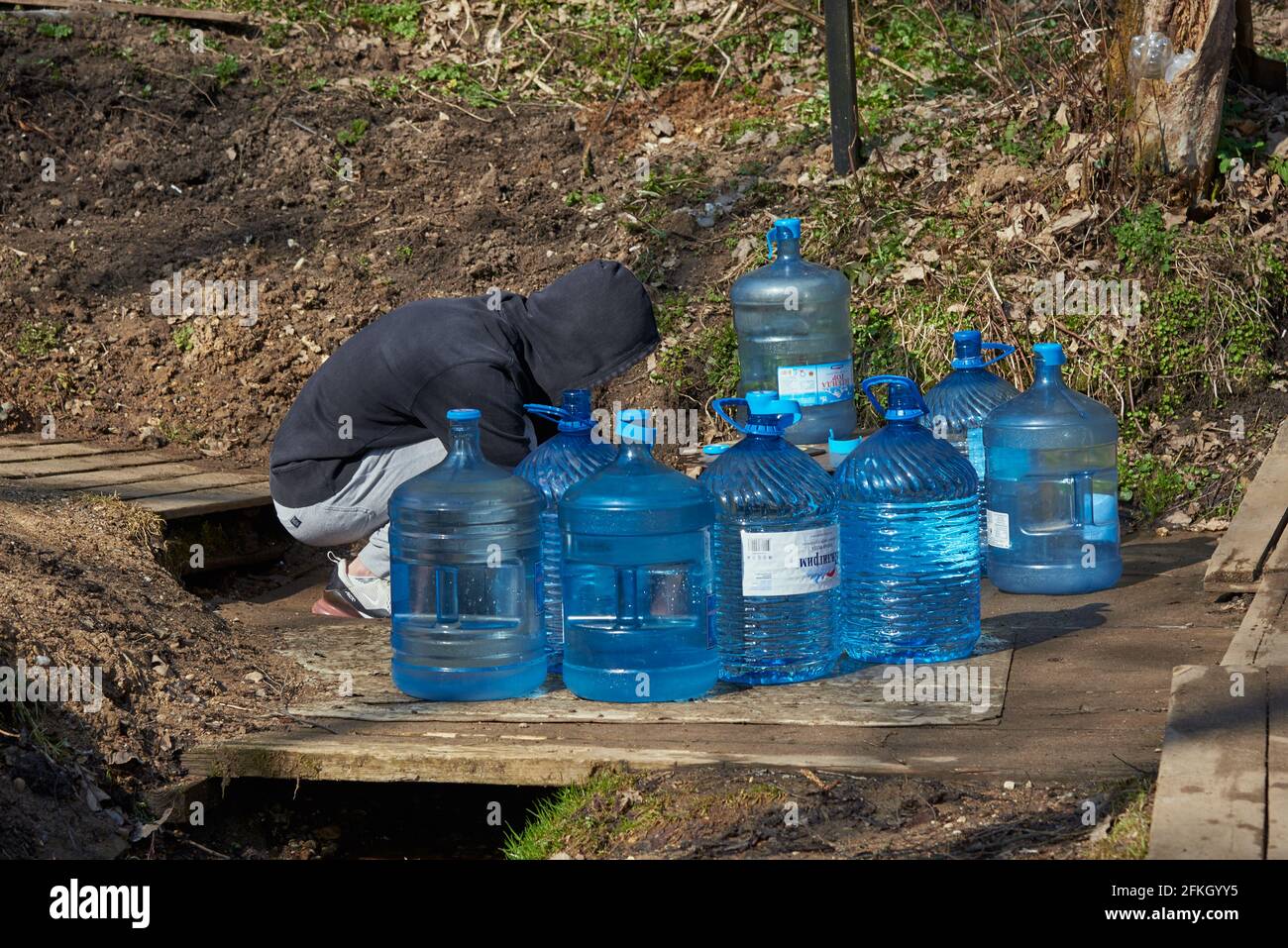 Russia, Moscow Region, April 2021. A young man collects water from a ...