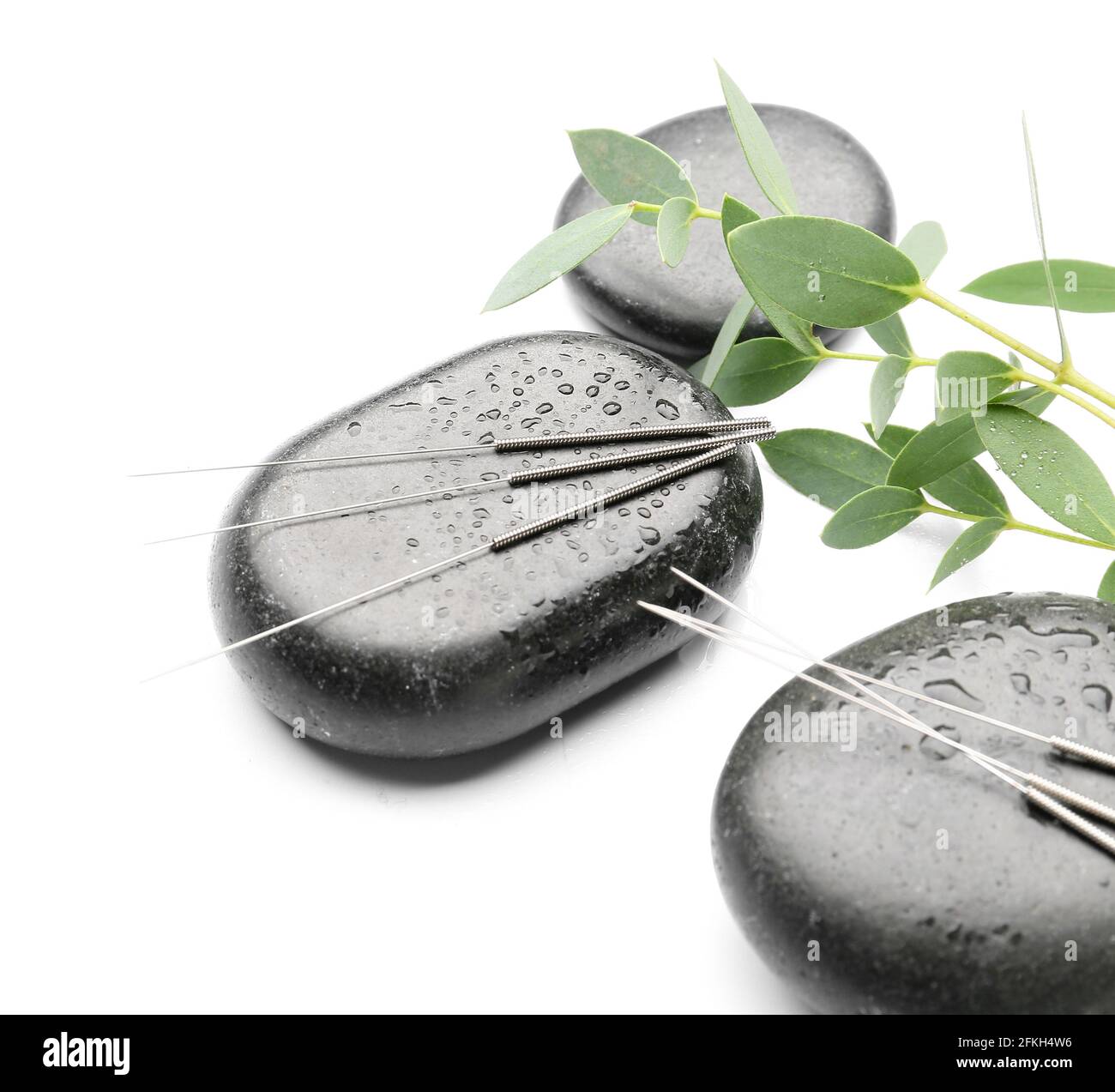 Acupuncture needles and spa stones on white background Stock Photo - Alamy