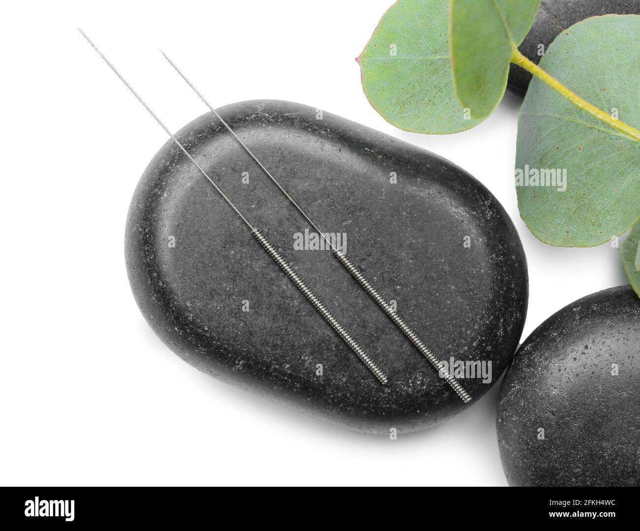 Acupuncture needles and spa stones on white background Stock Photo - Alamy