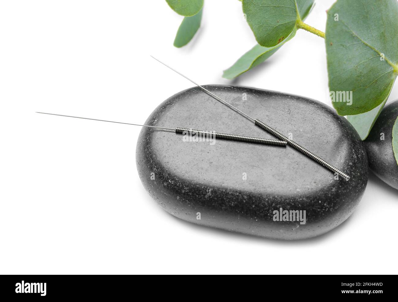 Acupuncture needles and spa stones on white background Stock Photo - Alamy