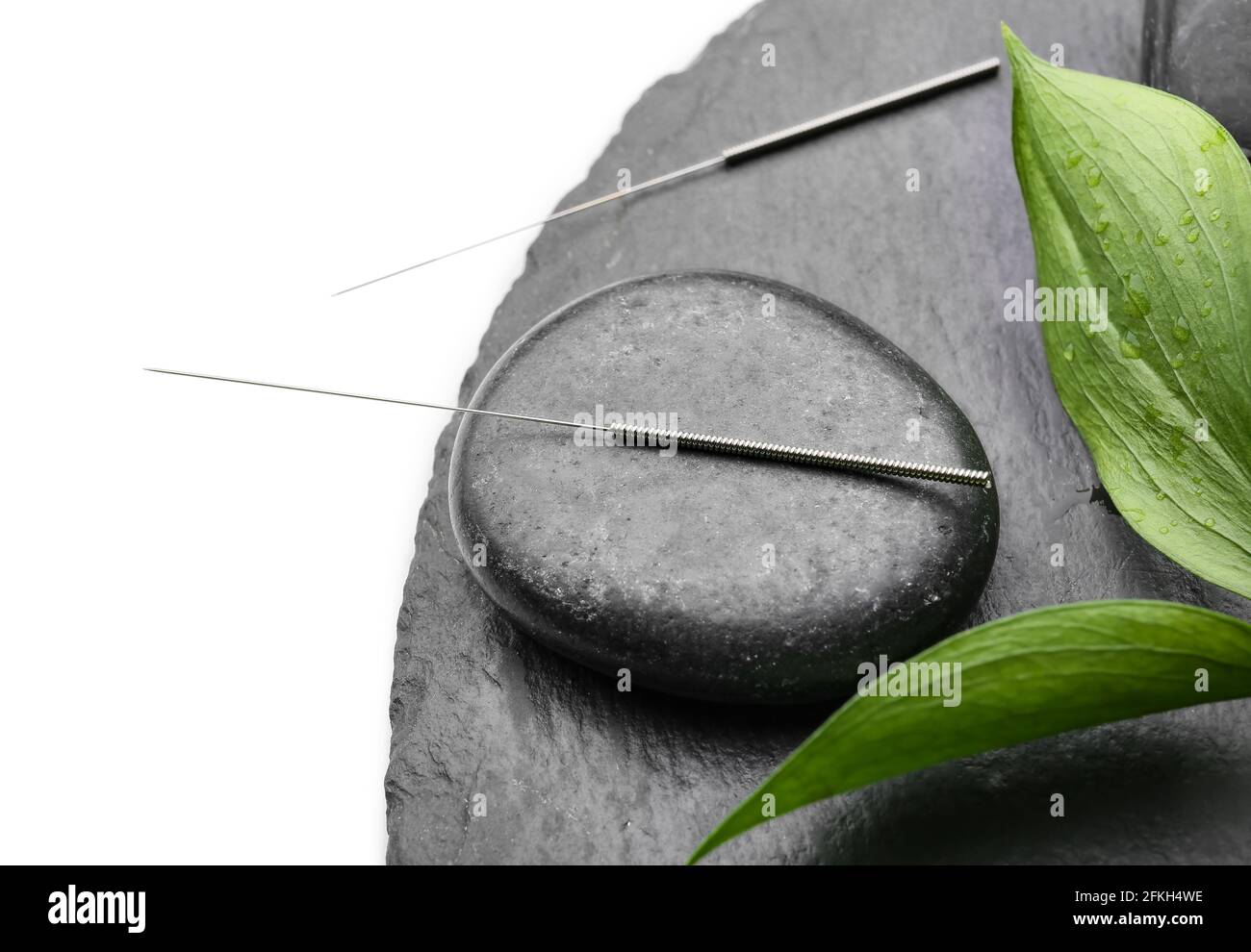 Acupuncture needles and spa stone on white background Stock Photo - Alamy
