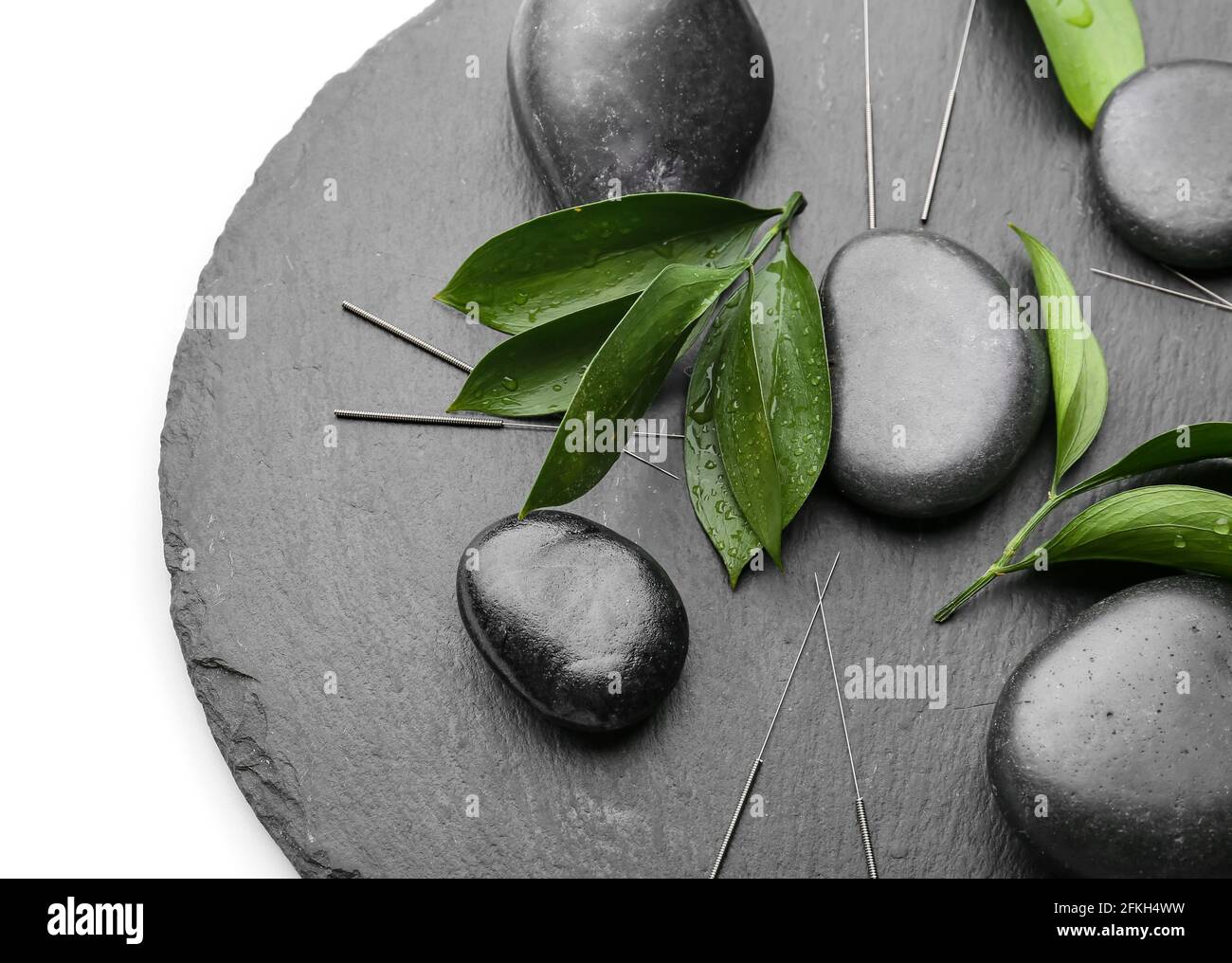 Acupuncture needles and spa stones on white background Stock Photo - Alamy