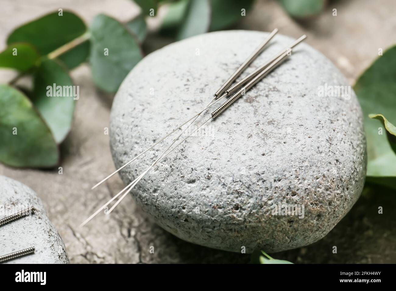 Acupuncture needles and spa stone on grey background Stock Photo - Alamy