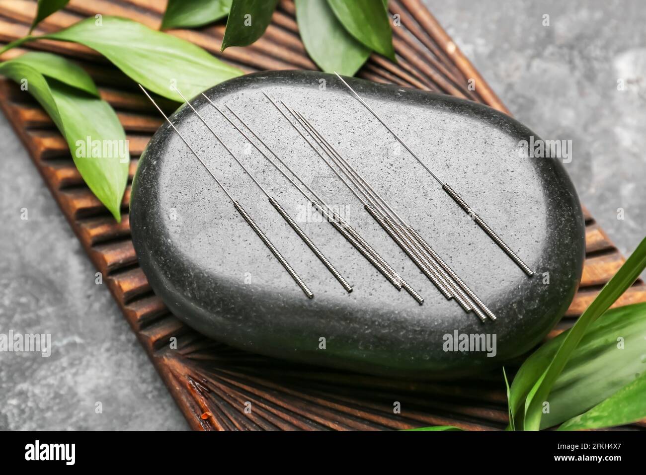 Acupuncture needles and spa stone on grey background Stock Photo - Alamy