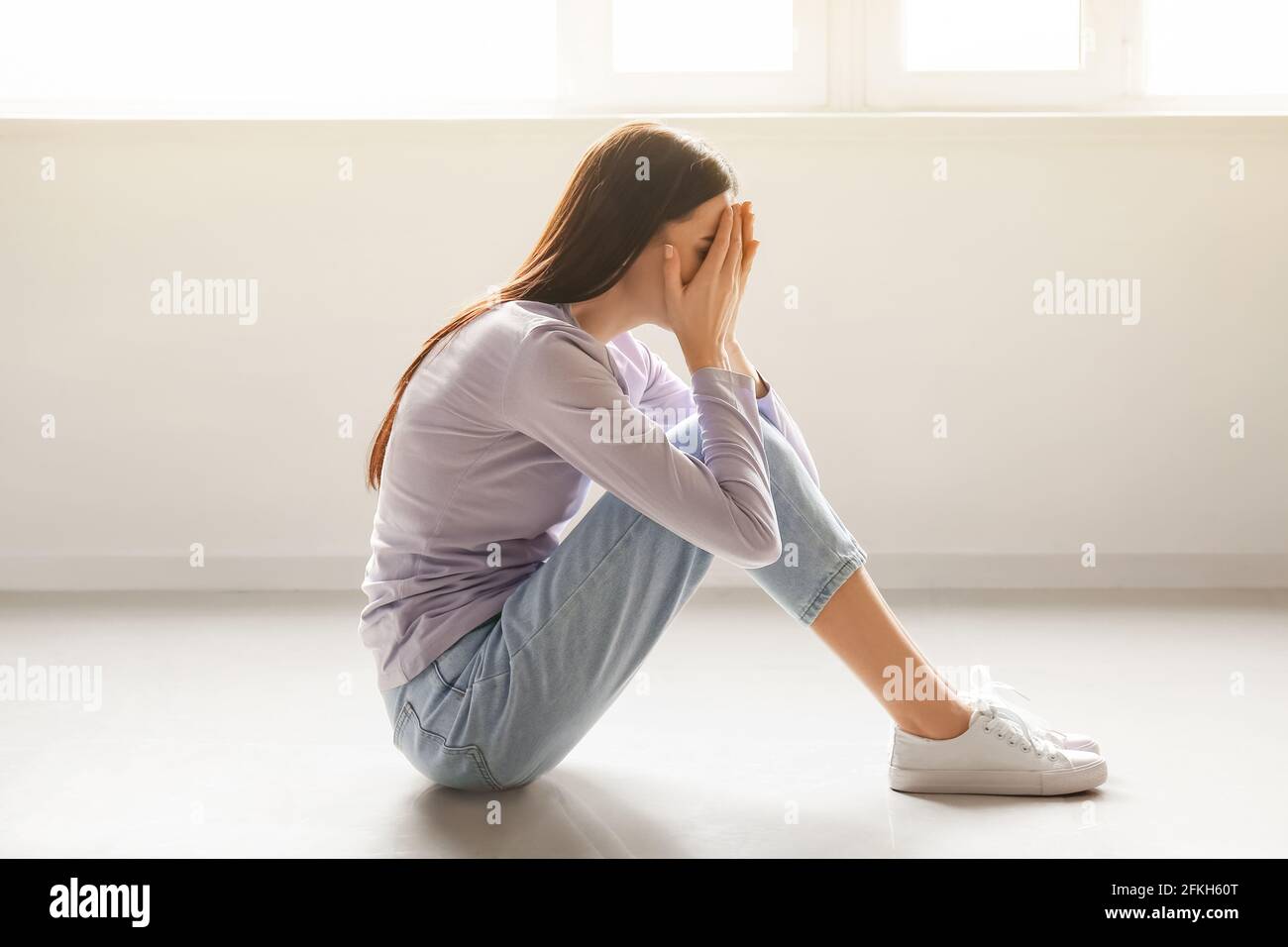 Sad woman sitting on floor in empty room Stock Photo - Alamy