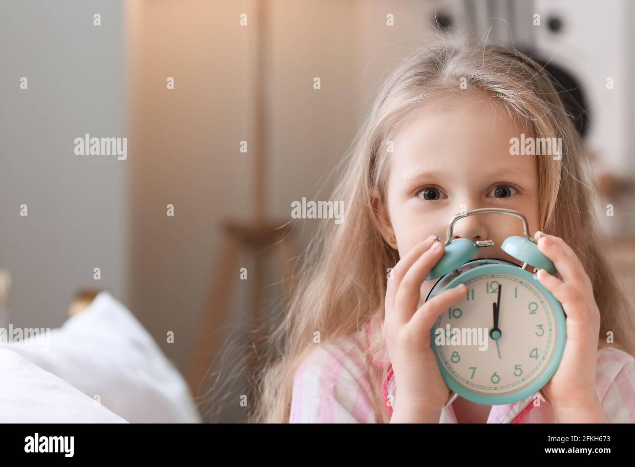 Cute little girl with alarm clock in bedroom Stock Photo - Alamy