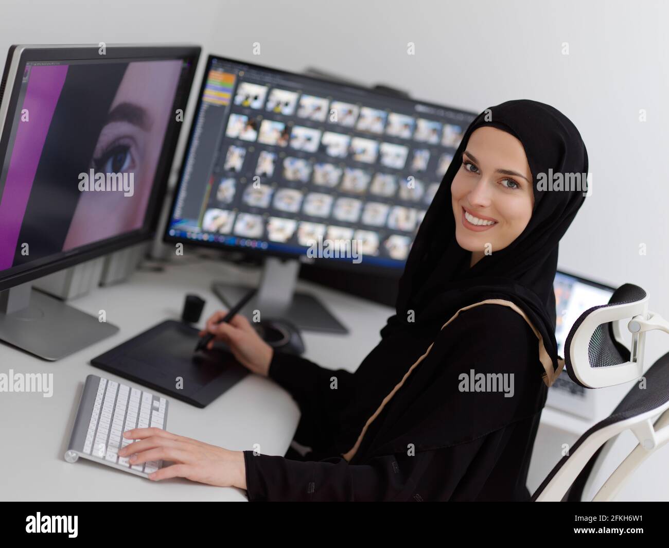 Muslim female graphic designer working on a computer using a graphic ...