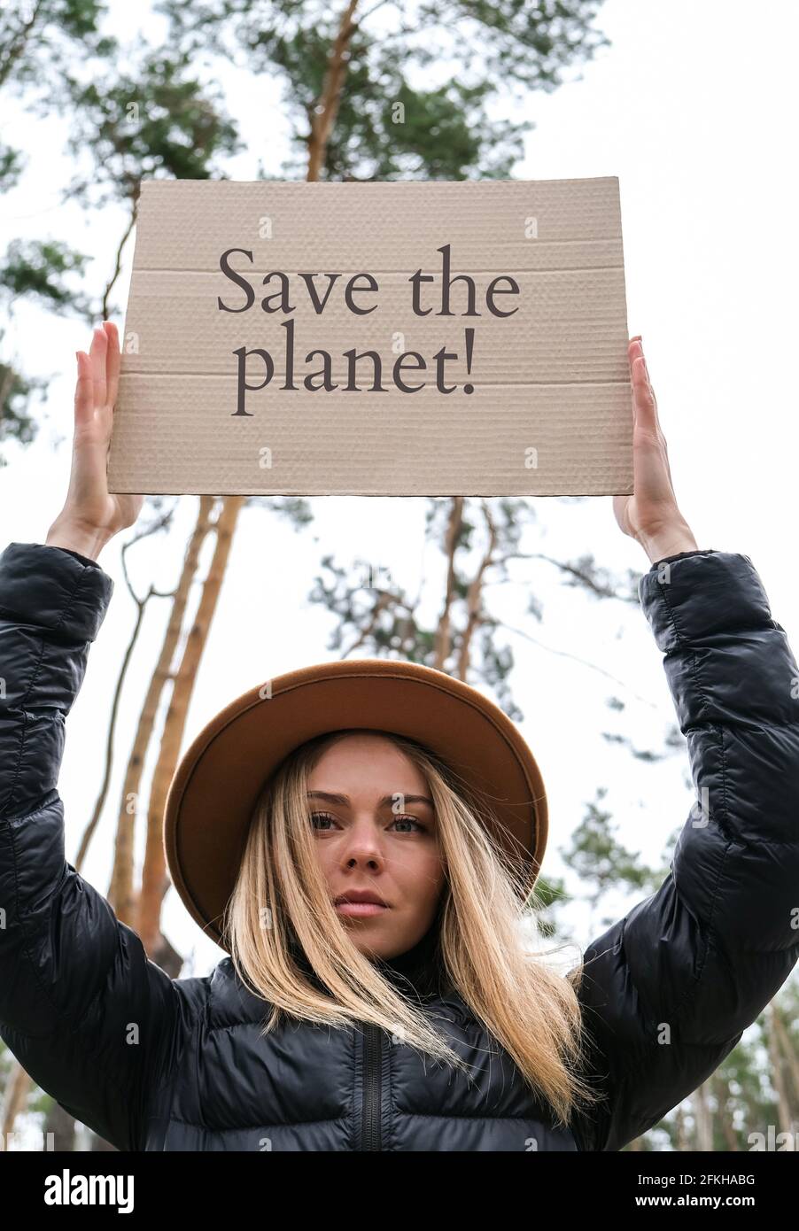 Portrait of caucasian young woman in hat holding cardboard with text ...