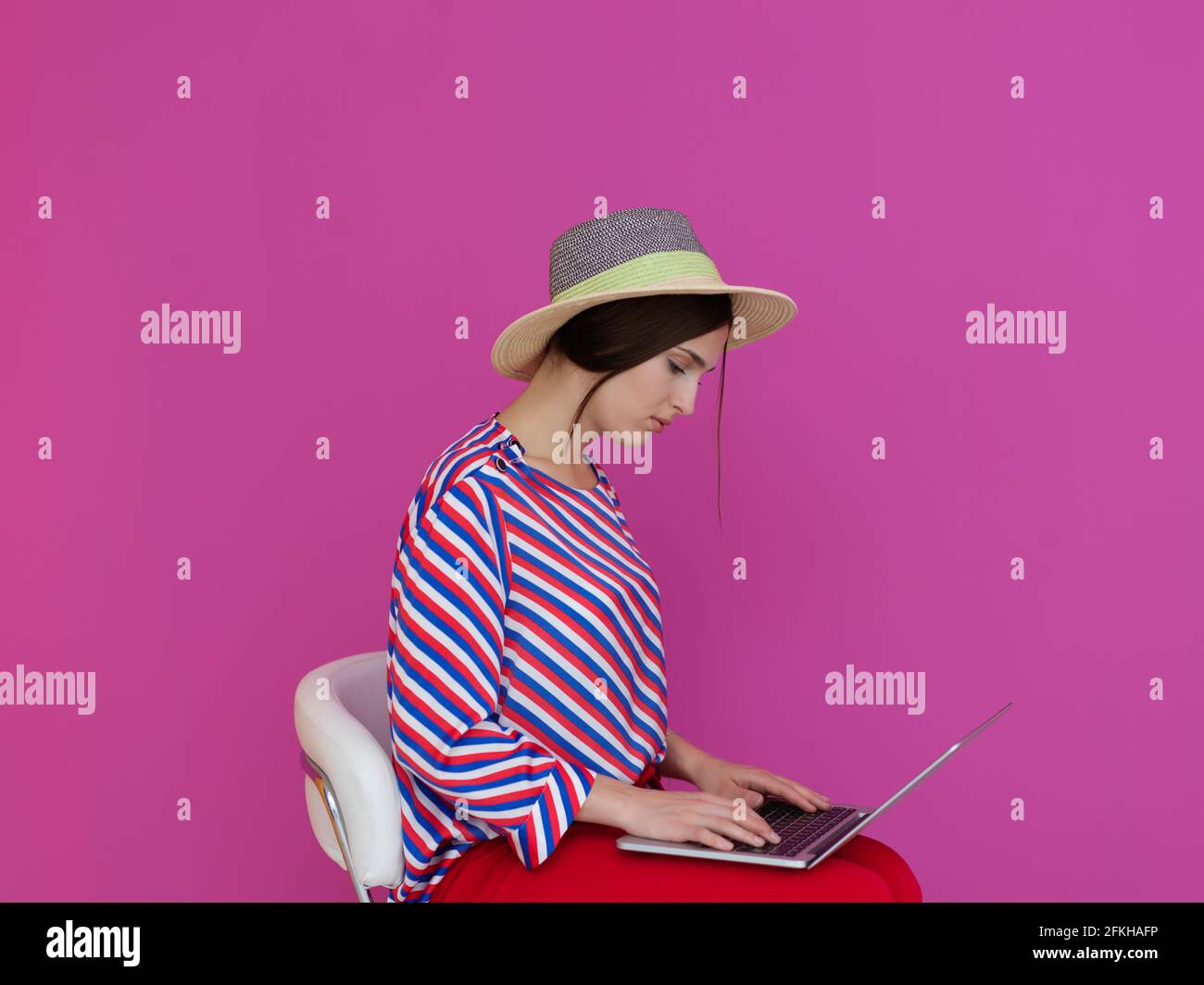 Portrait of young woman sitting on the chair and holding laptop on the ...