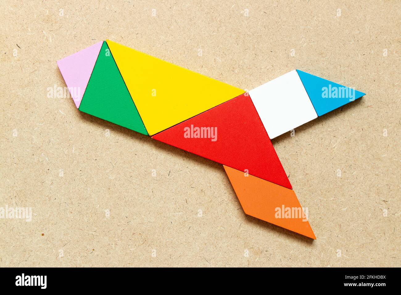 Color tangram puzzle in missile or rocket shape on wood background ...