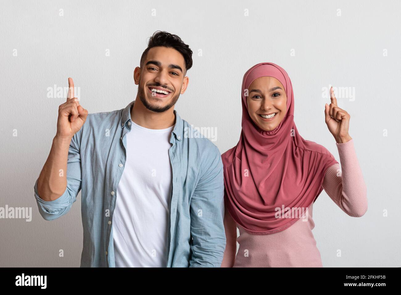 Idea Concept. Cheerful young muslim couple pointing fingers up Stock ...