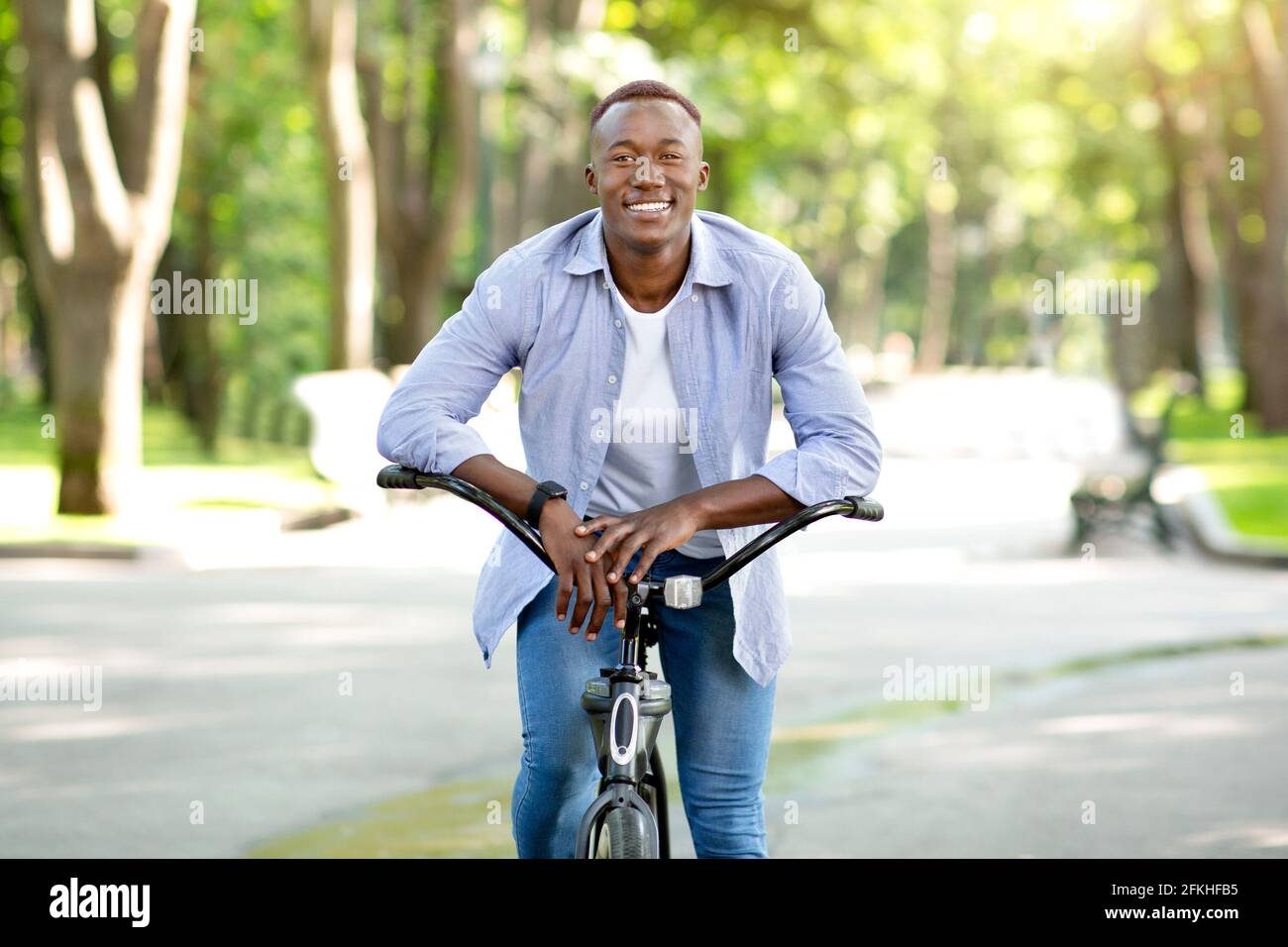 Urban adventure concept. Happy African American guy on fun bicycle ride ...