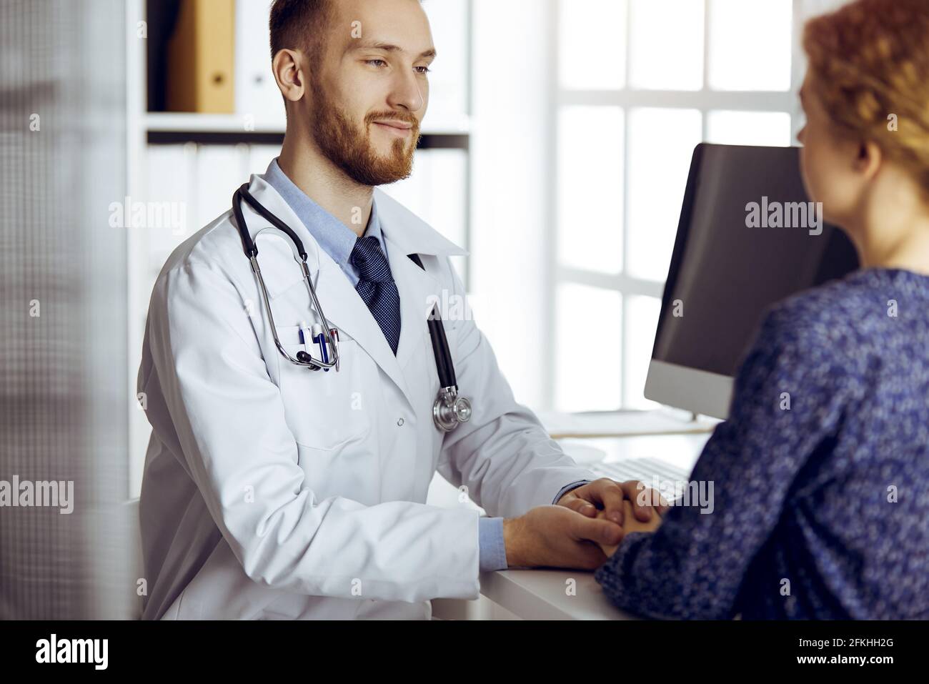 Friendly red-beard doctor reassuring his female patient. Medical ethics ...